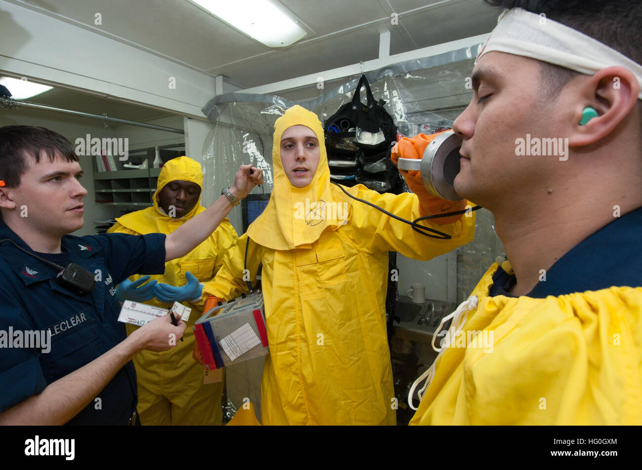 Machinist's Mate 2nd Class Brenton Robbins, center, uses a frisker on ...