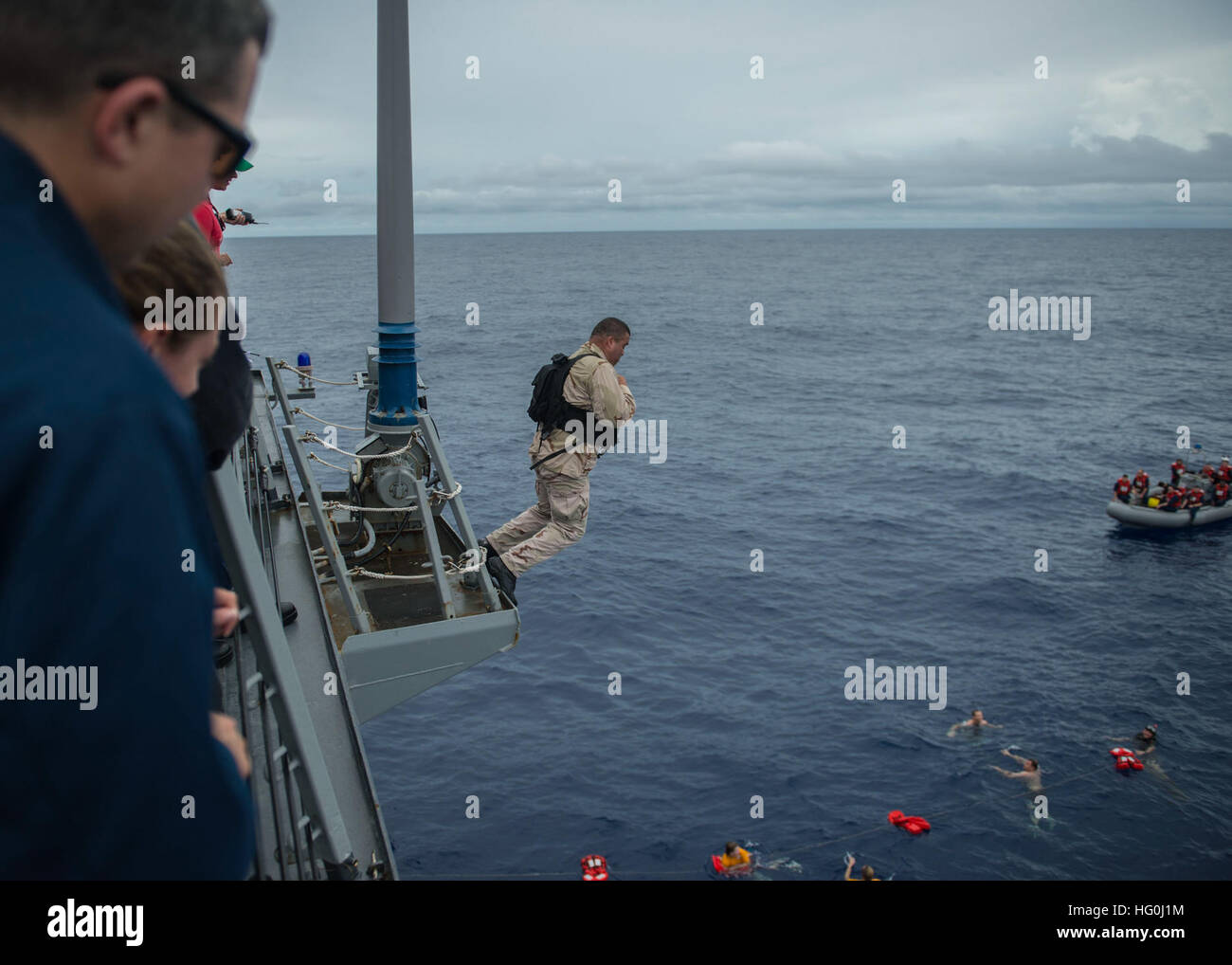 U.S. Navy Boatswain's Mate 1st Class Jose Valdez, center, jumps from ...