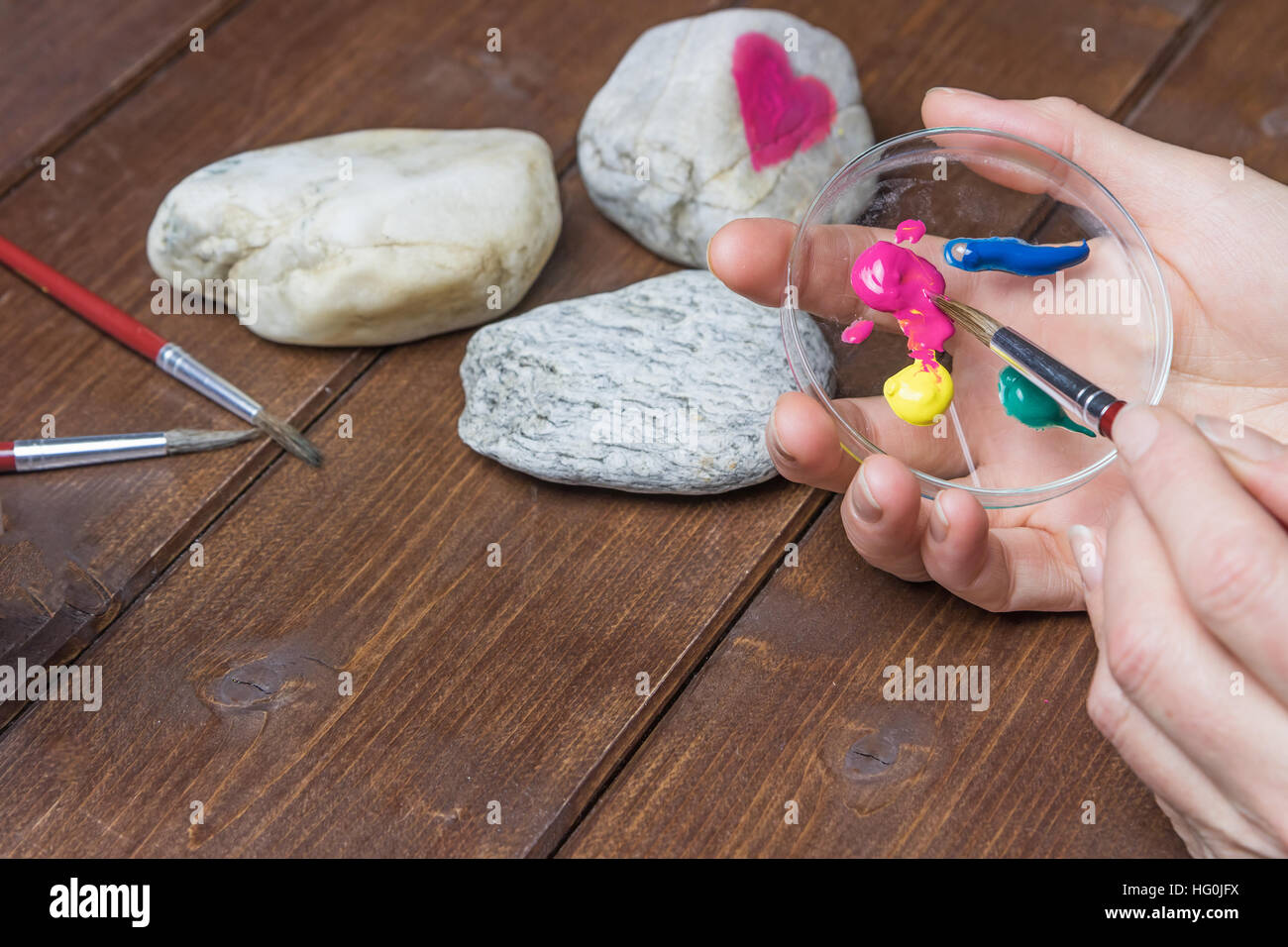 Woman's hand is is smudging colors in a glass bowl before painting an ...