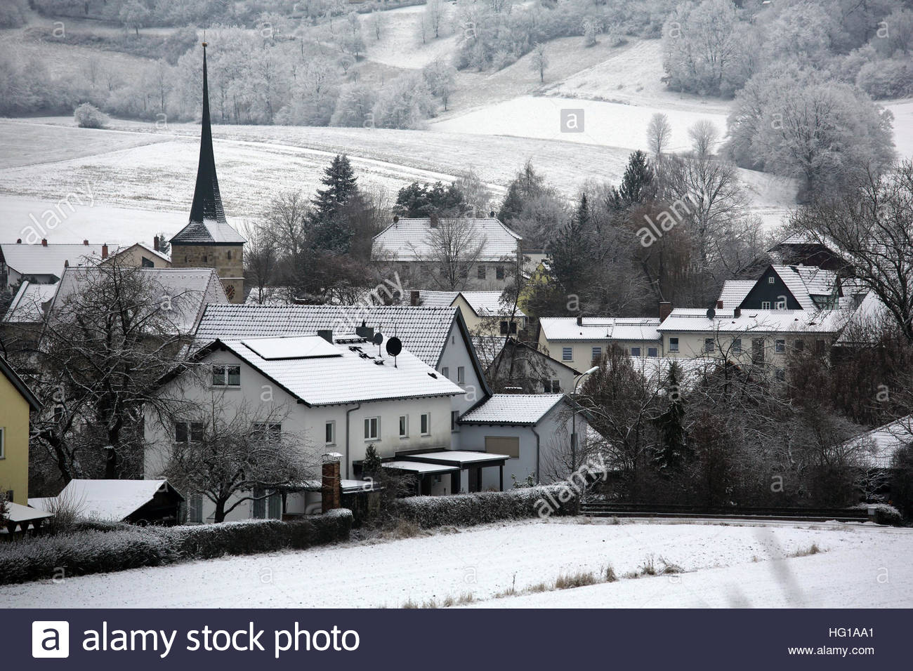 A village church spire and snow-covered rooftops in Bavaria, Germany on ...