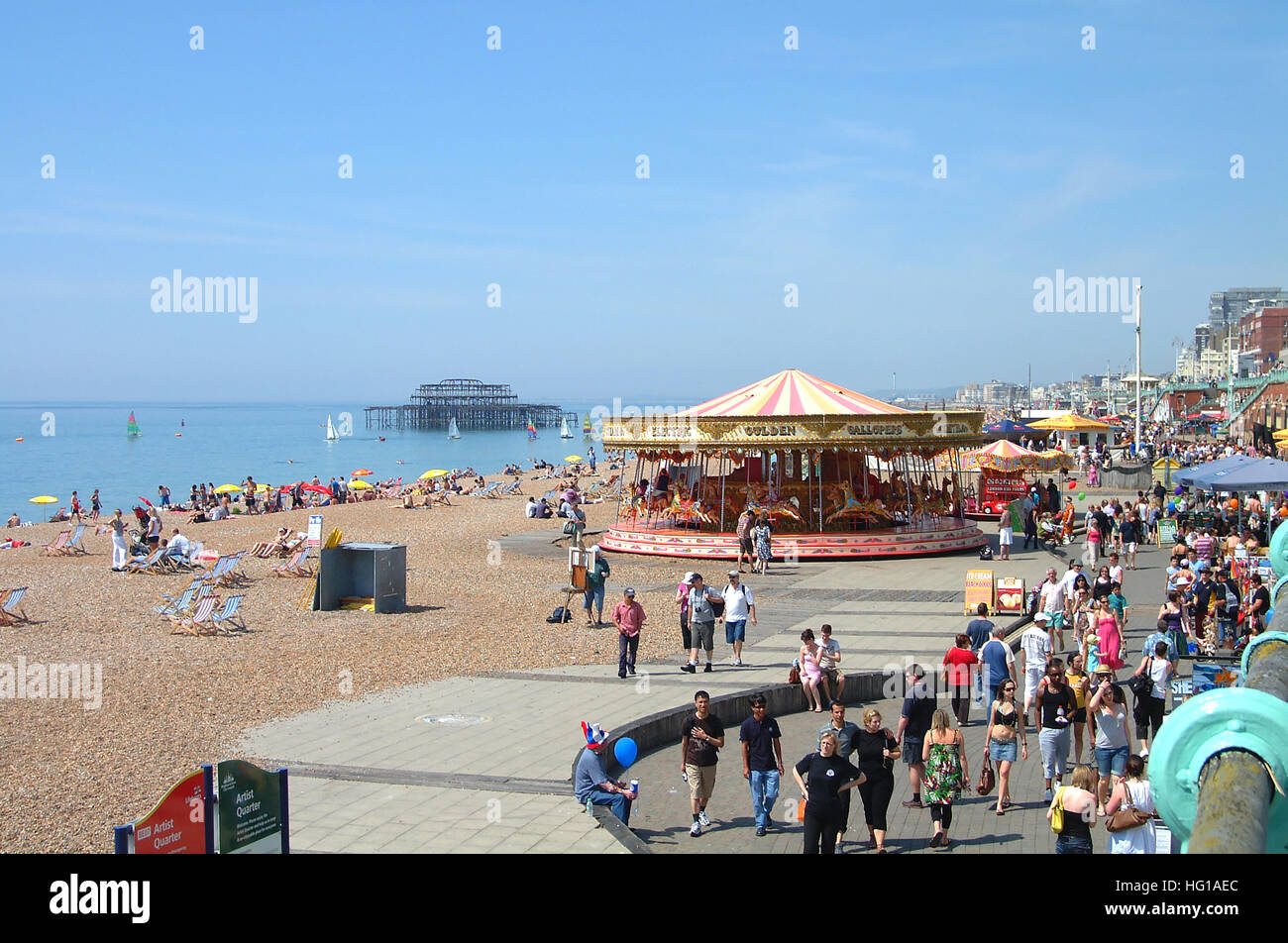 People on Brighton seafront, carousel, cafe and the remains of Old west ...