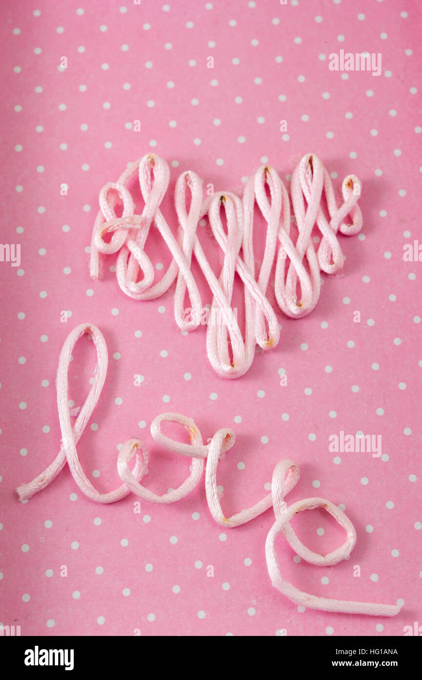Word love made out of thread on pink background Stock Photo - Alamy