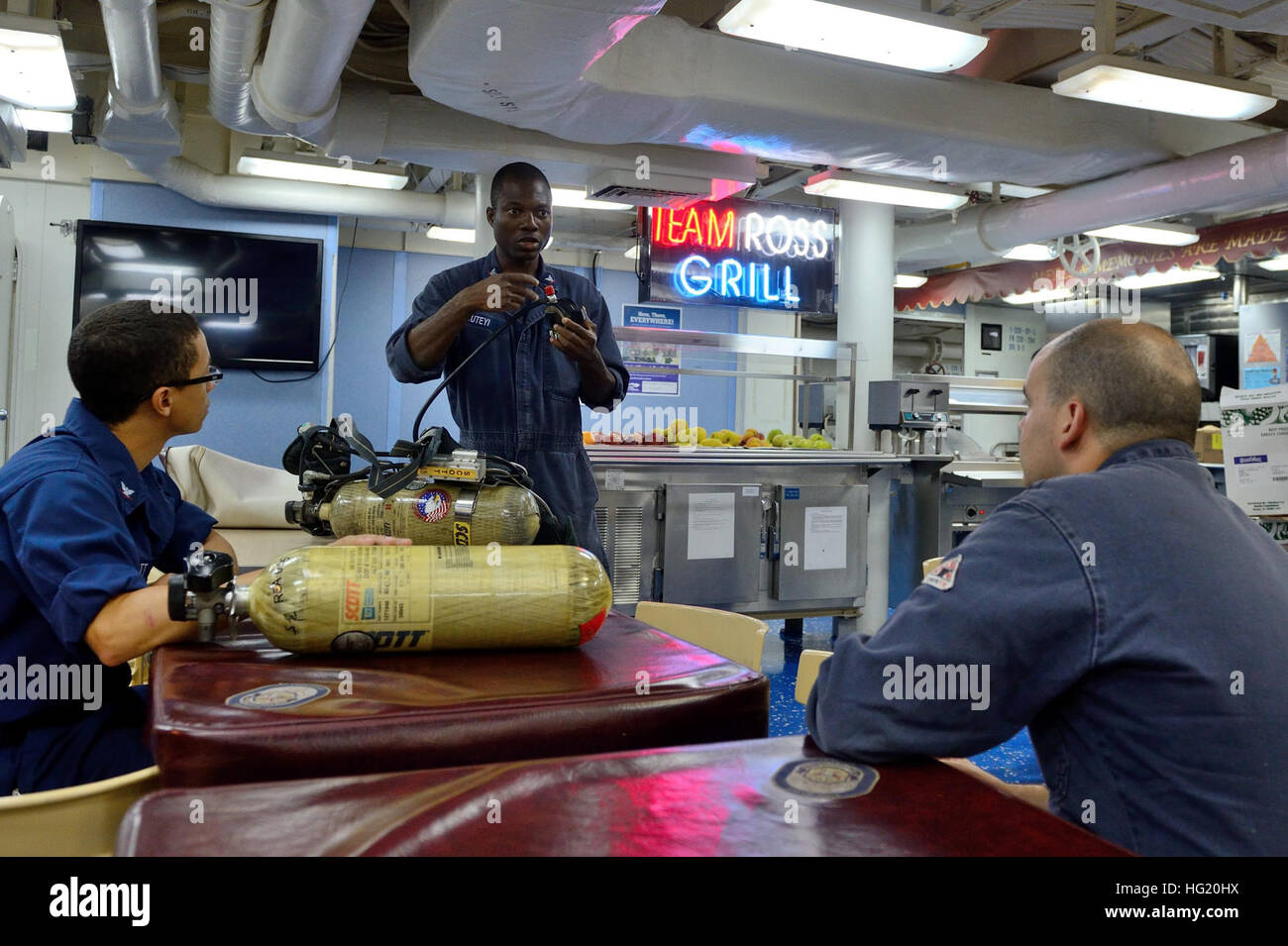U.S. Navy Damage Controlman 3rd Class Bamidele Kuteyi, center, explains ...