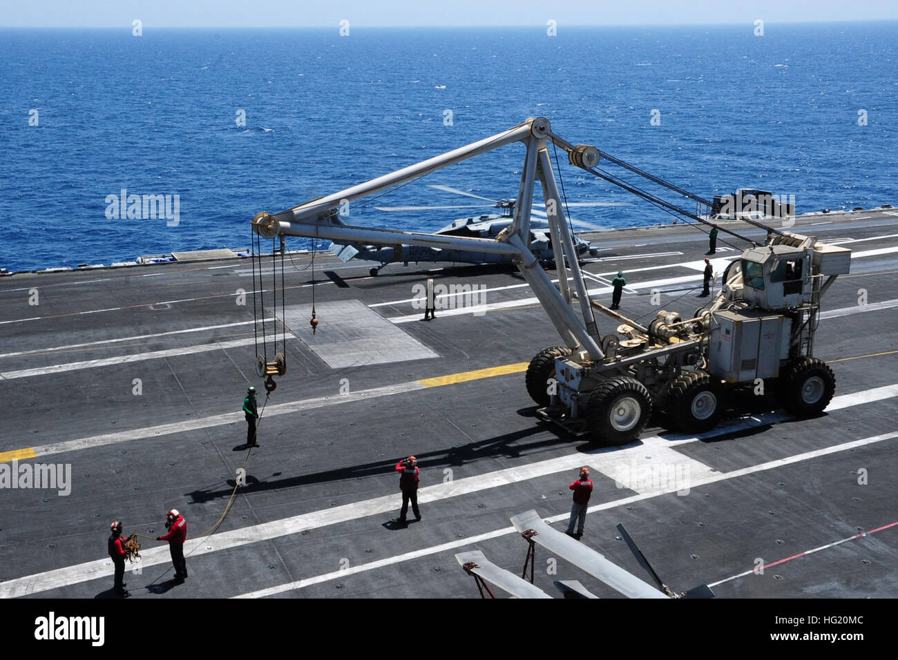U.S. Sailors direct a crash and salvage crane on the flight deck of the ...