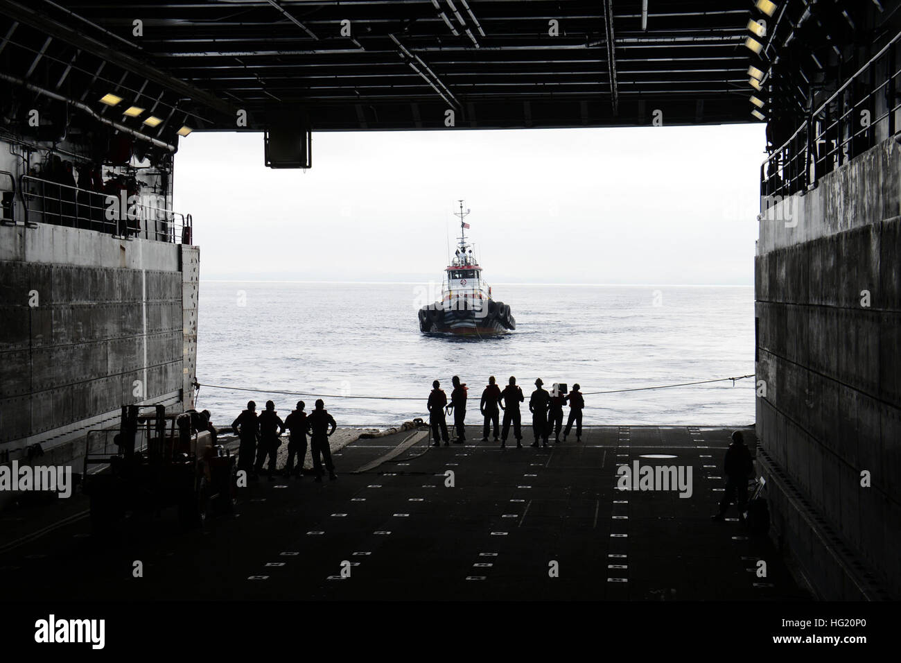 Sailors prepare for a towing exercise with a tug aboard amphibious ...