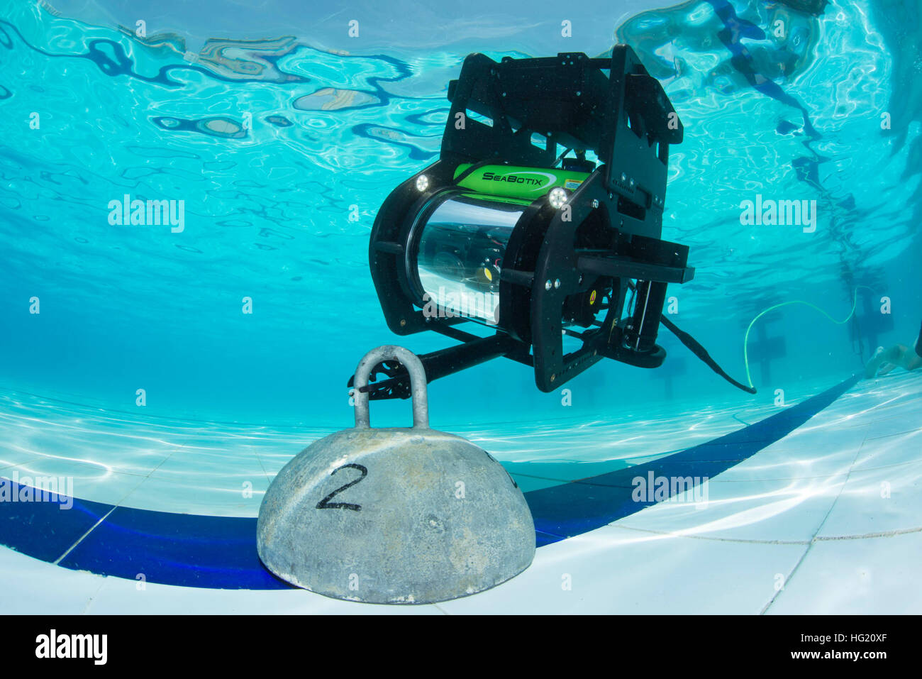 A remote operated underwater vehicle clamps onto a weight during a pool ...