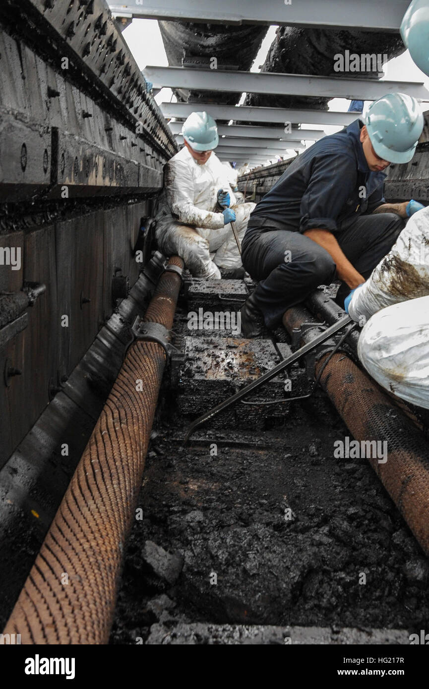 Sailors use crowbars to clean grease out of the trench in catapult one ...