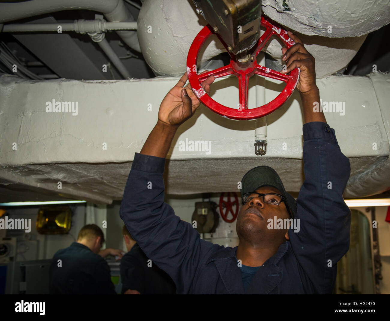 Damage Controlman Fireman Dequan Fort closes a valve on the mess decks ...