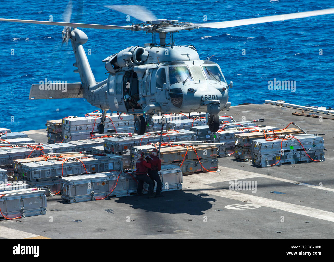 Weapons Department Sailors attach an ordnance canister to an MH-60S Sea ...