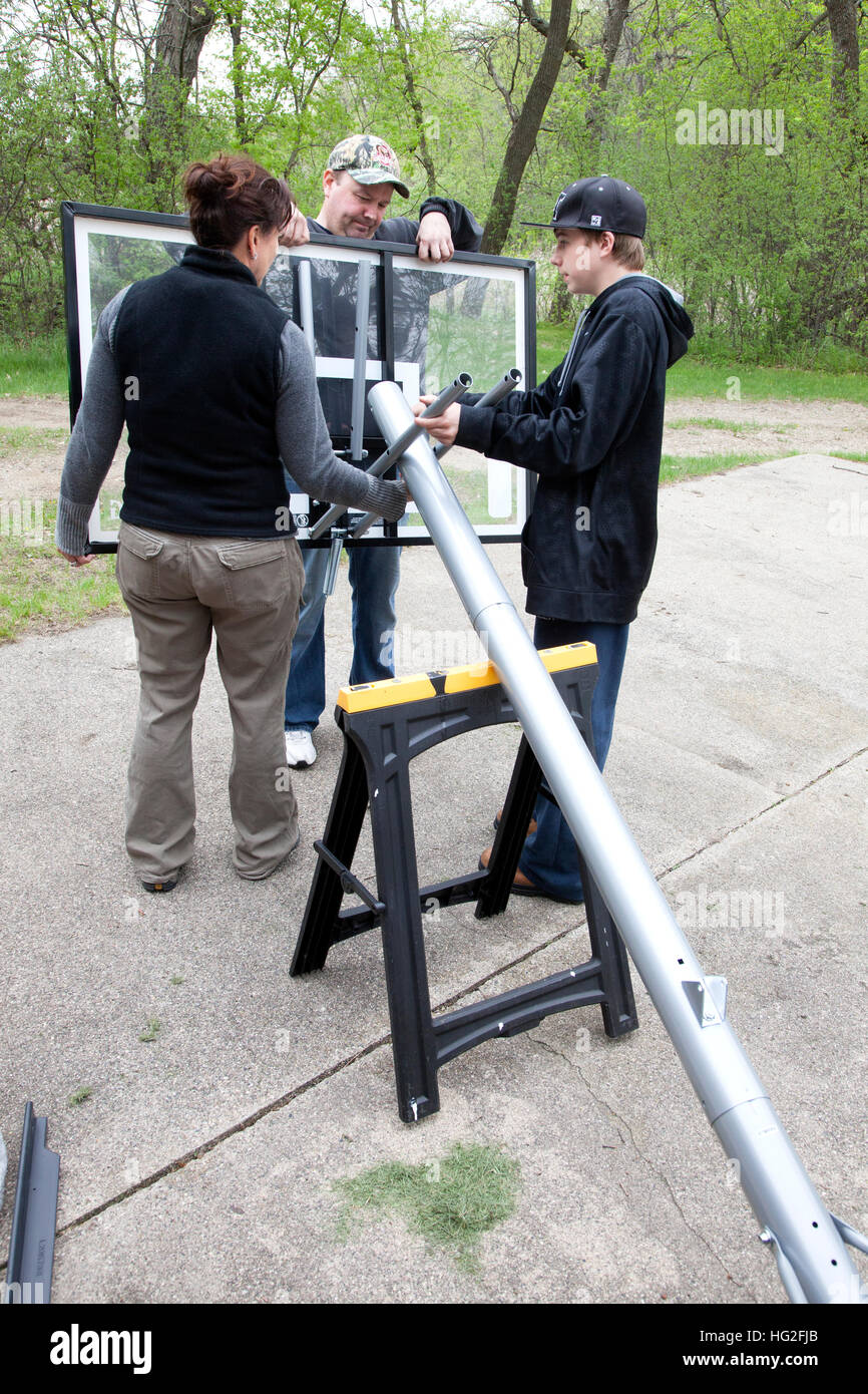 Family assembling portable basketball hoop. Mom, dad and teen son ...
