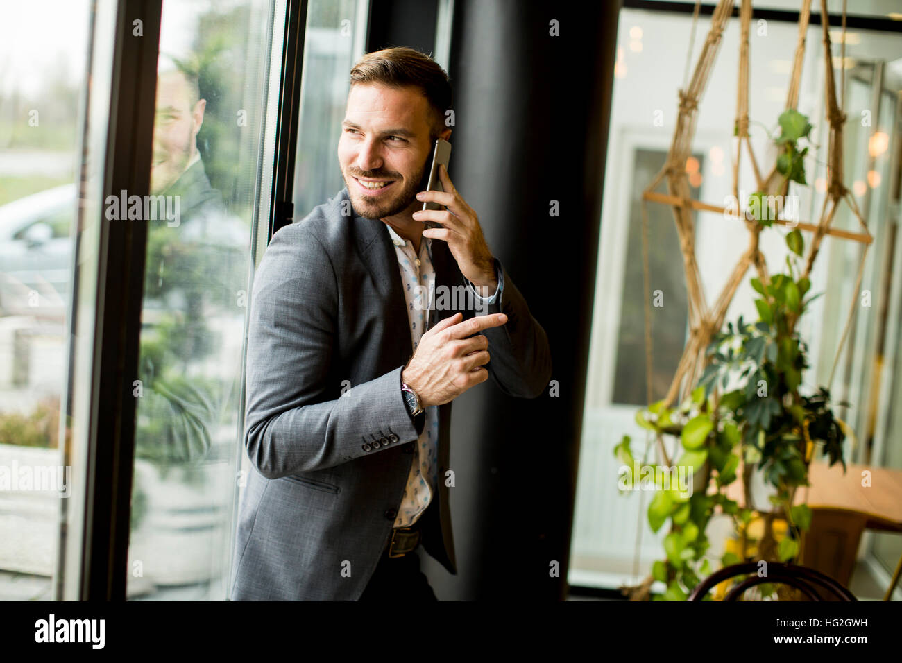 Young man standing and using mobile phone Stock Photo - Alamy