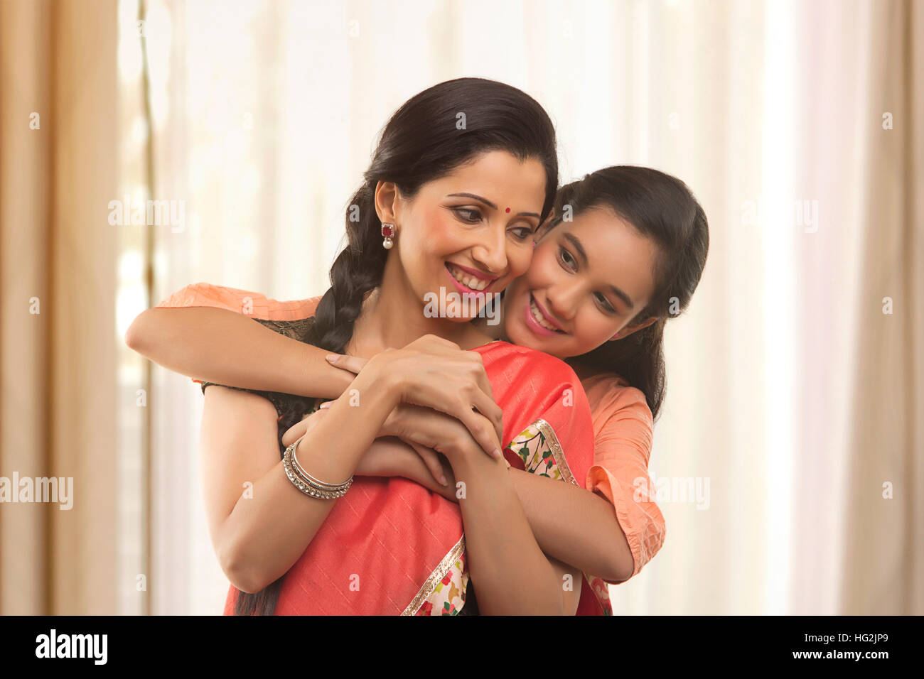 Indian teenage daughter hugging her mother from the back Stock Photo - Alamy