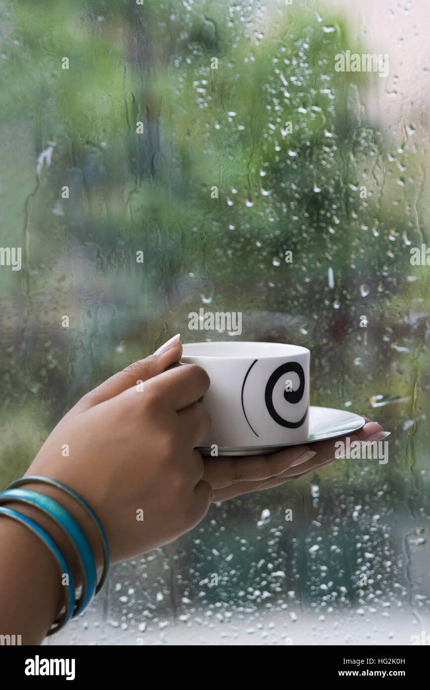 Close up of cup in woman hand in front of rainy window glass Stock ...