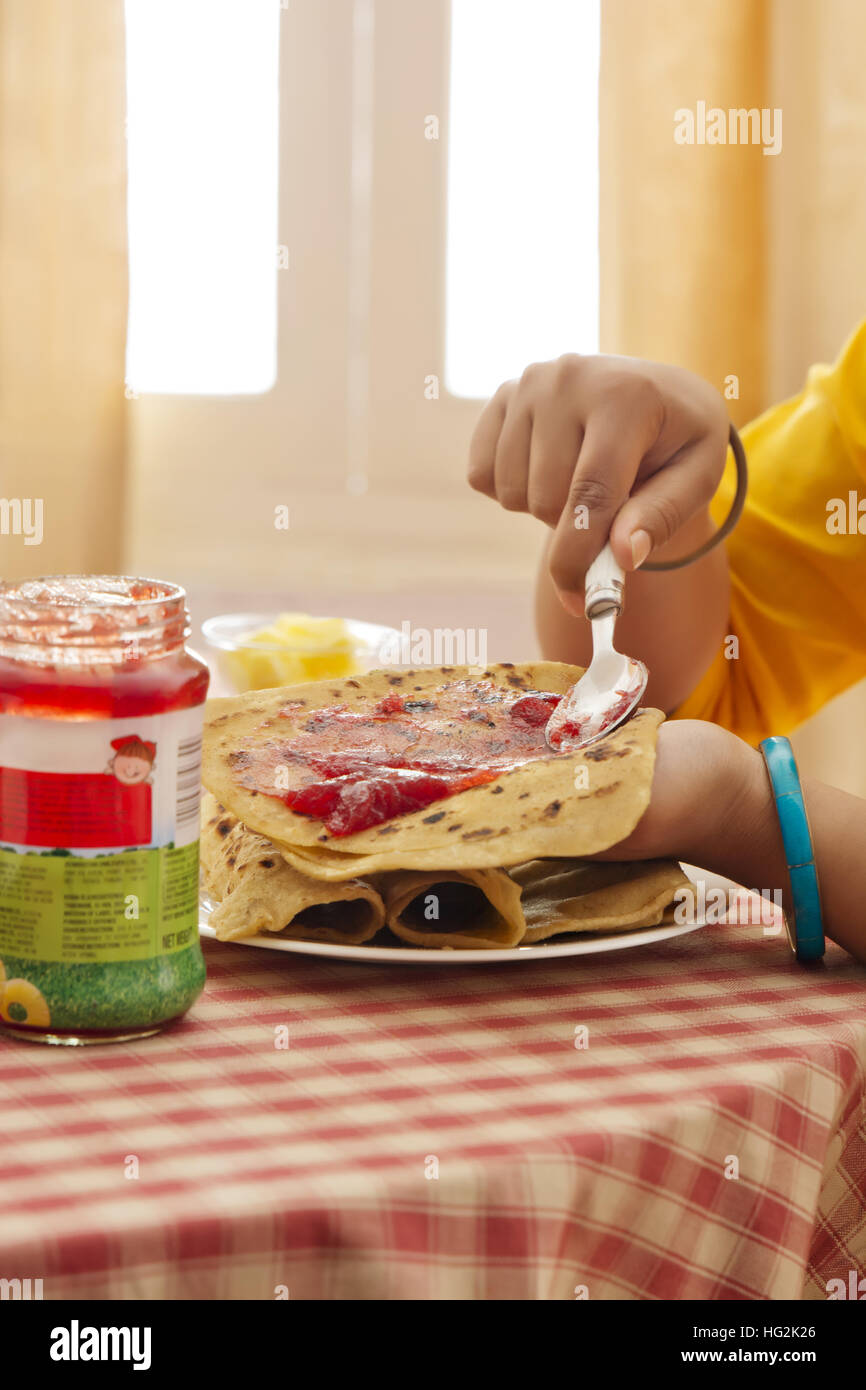 Woman spreading jam on paratha Stock Photo - Alamy