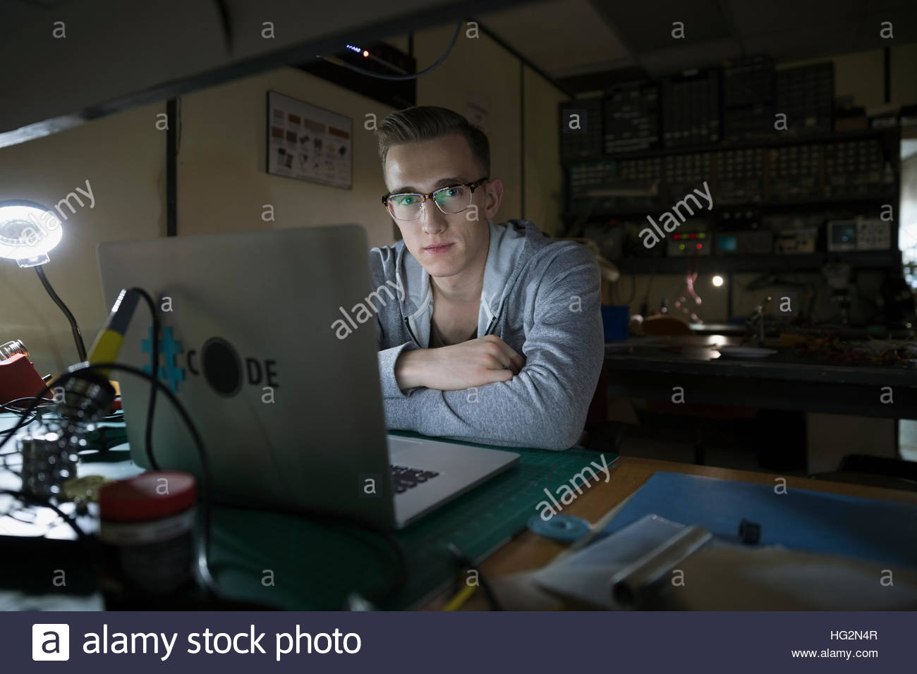 Portrait confident male computer programmer working at laptop in dark ...