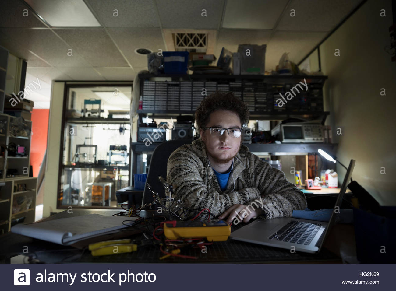 Portrait serious computer programmer working at laptop in dark office ...