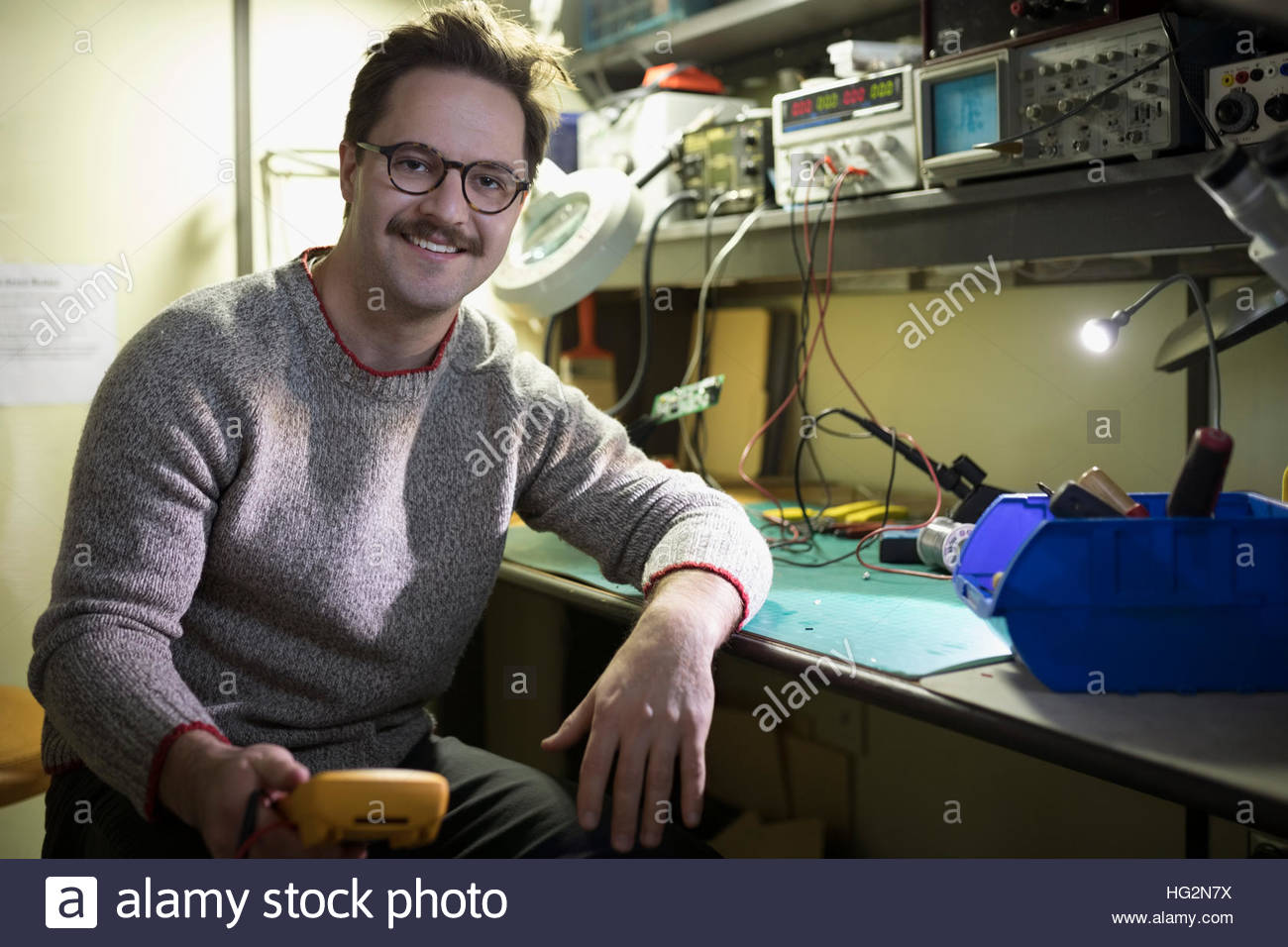 Portrait smiling male electronics engineer at workbench in workshop ...