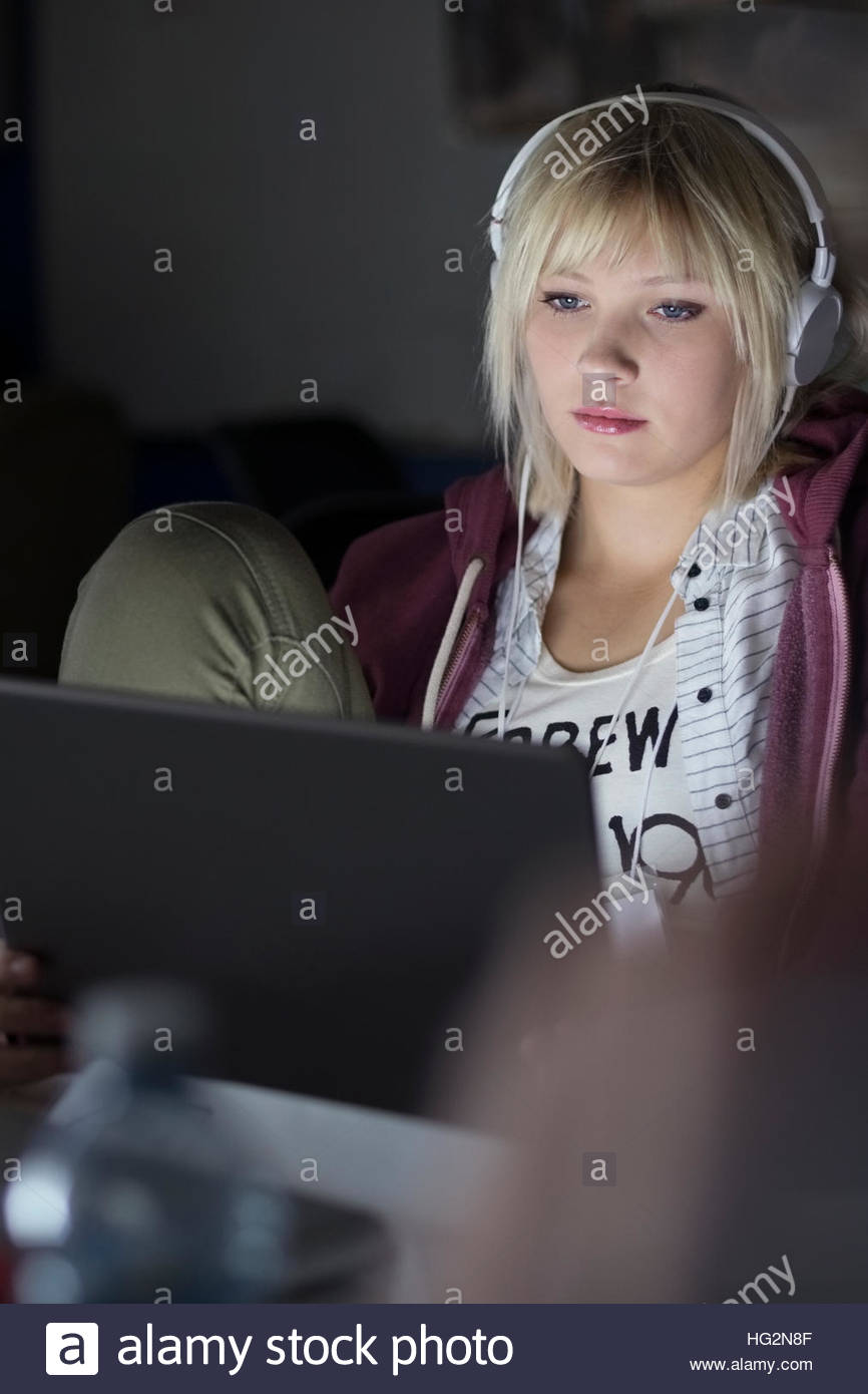 Focused female hacker working hackathon with laptop and headphones ...