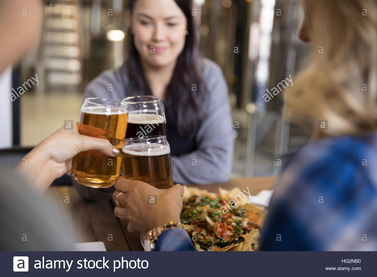 Female friends toasting beers at brewery restaurant table Stock Photo ...