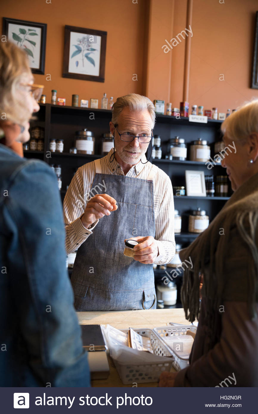Male spice shop owner helping female customers at counter Stock Photo ...
