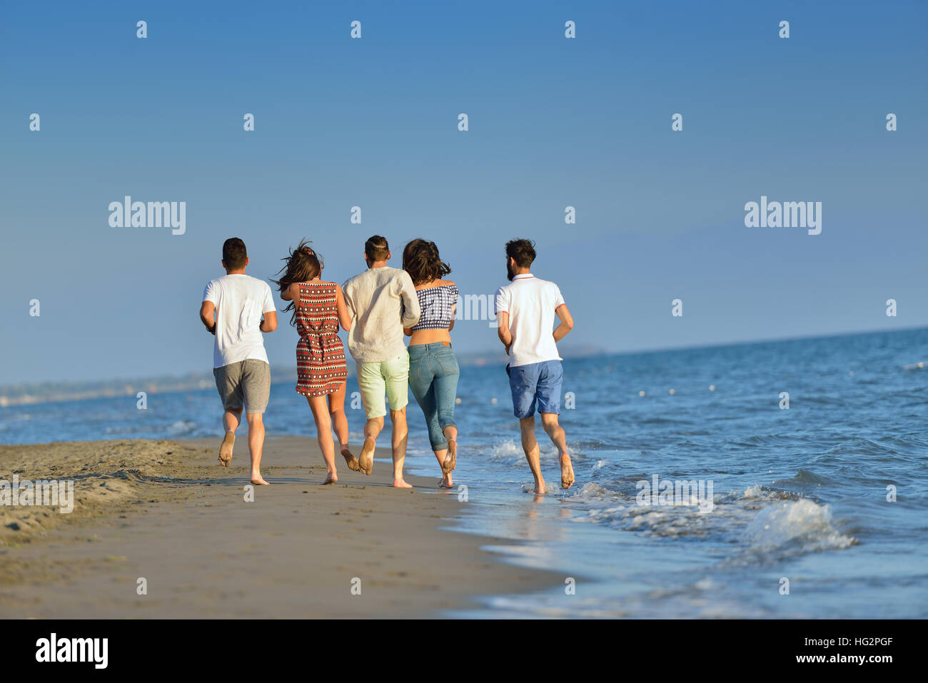 happy young people group have fun white running and jumping on beacz at ...