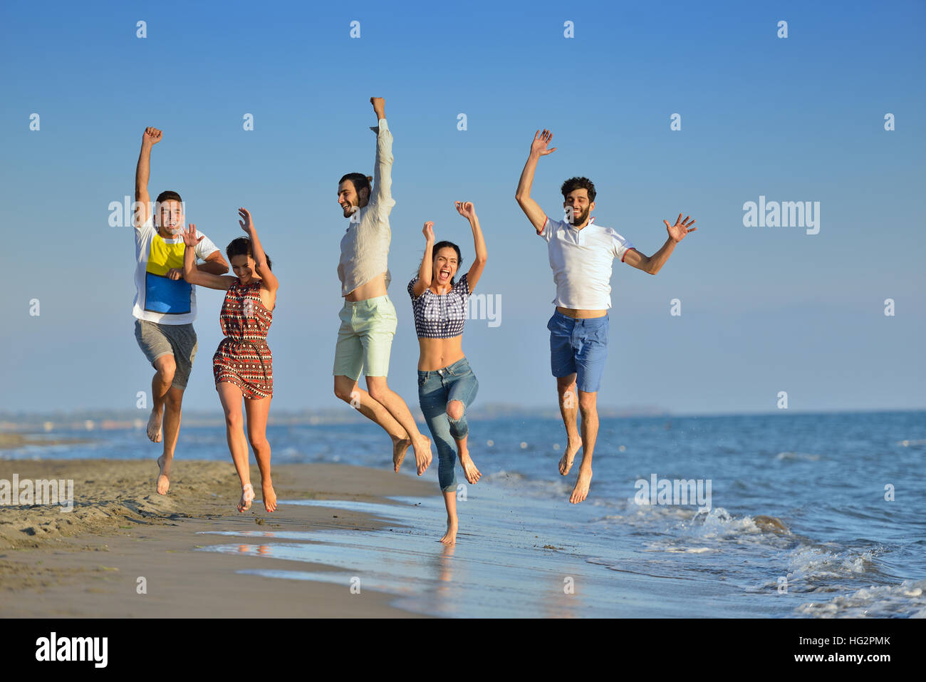 happy young people group have fun white running and jumping on beacz at ...