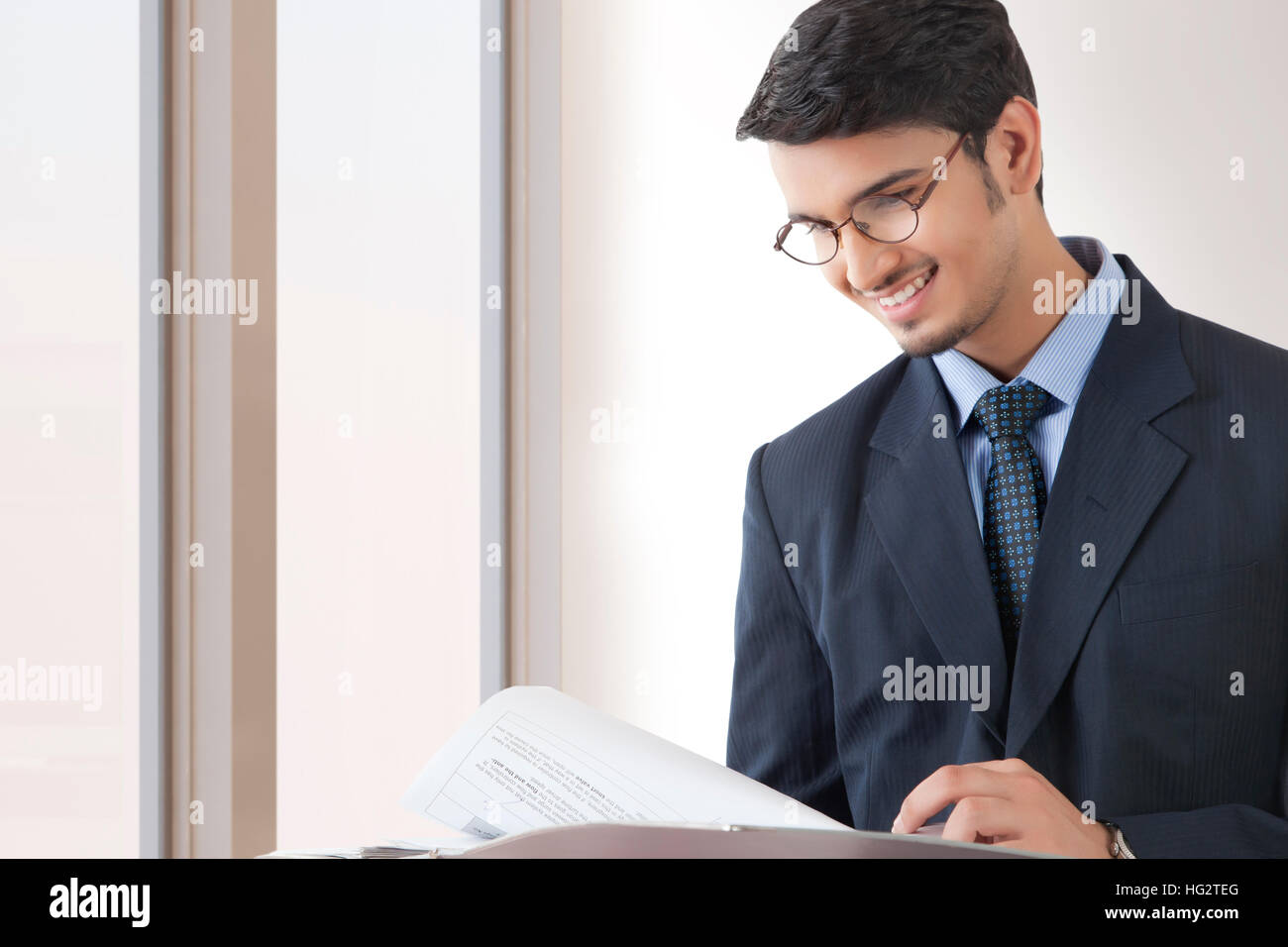 Young professional man looking at documents in file with smile on face ...