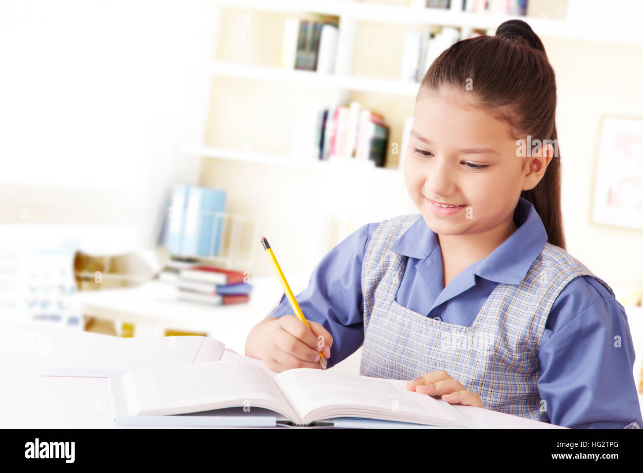 Girl in school uniform doing her homework Stock Photo - Alamy