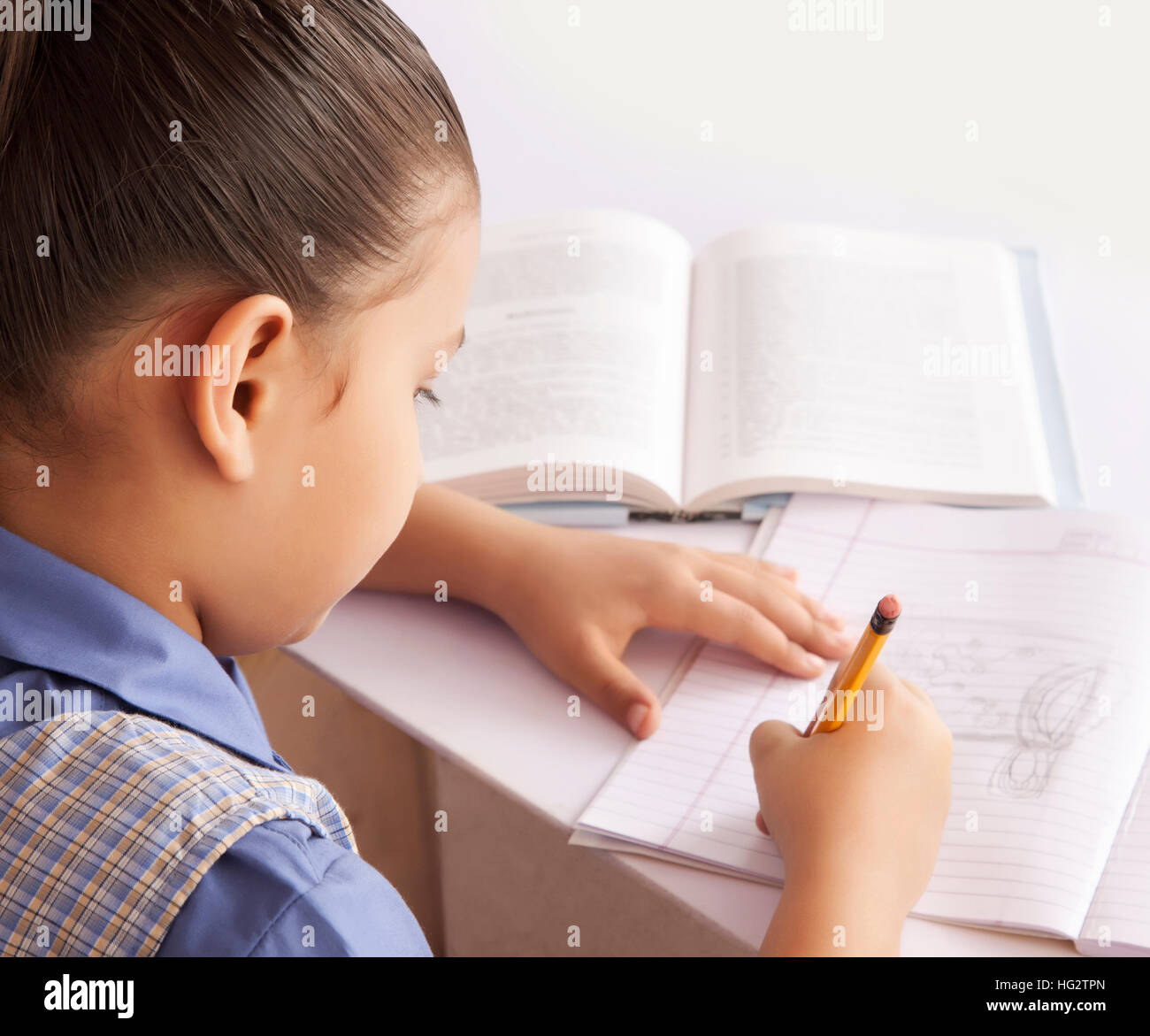 Girl in school uniform doing her homework Stock Photo - Alamy