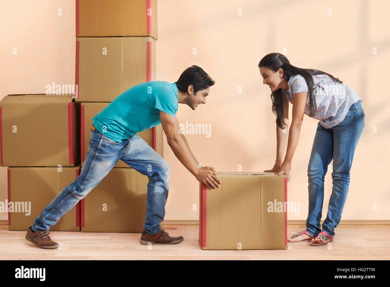 Couple Pushing Cardboard Box Stock Photo - Alamy