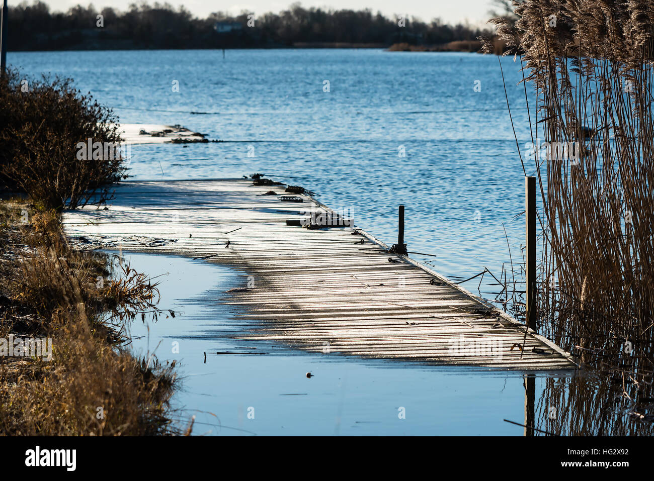 Wooden pier almost submerged and with icy frost on the dry areas ...