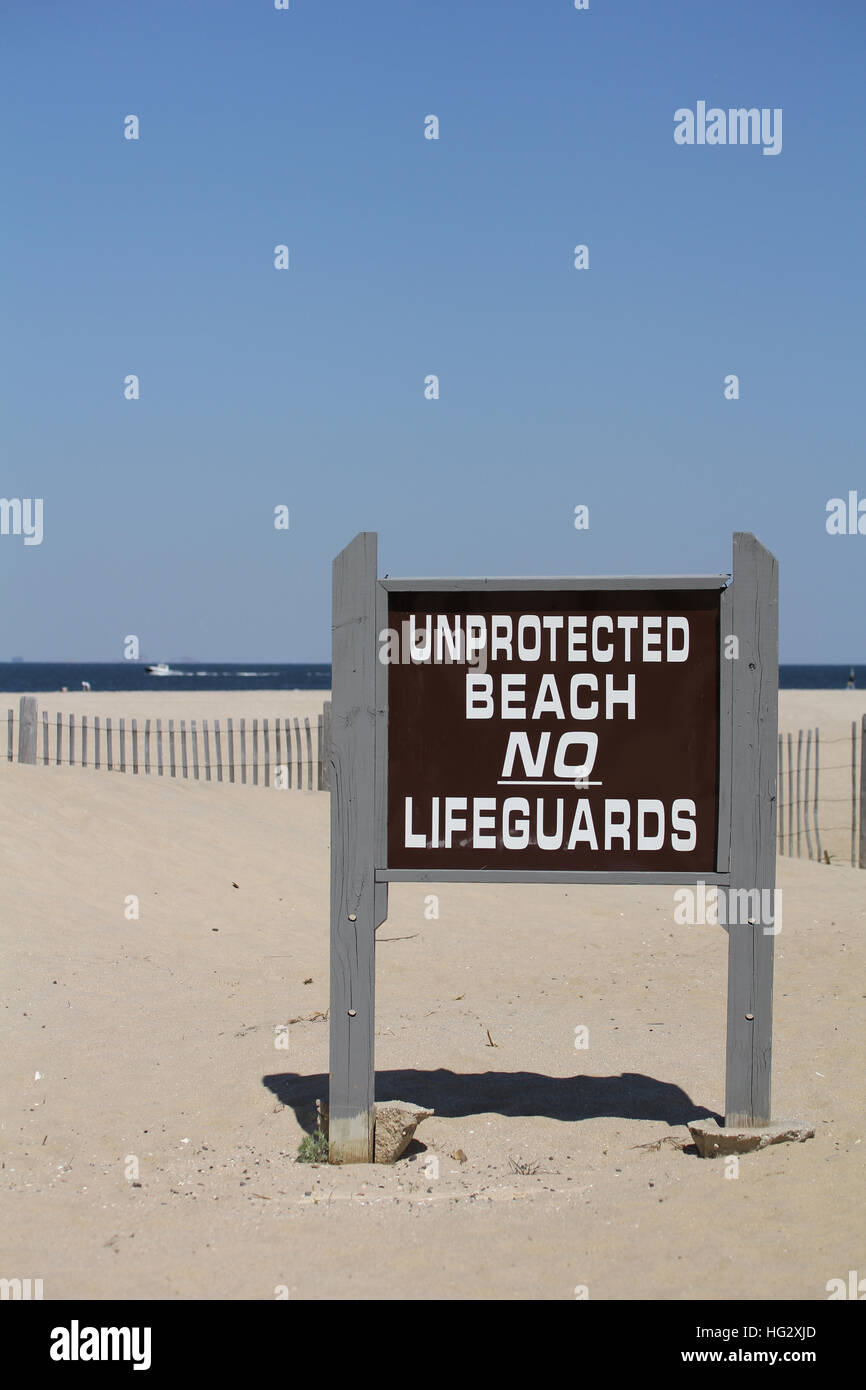 A sign reads "Unprotected Beach No Lifeguards." A clear blue sky is ...