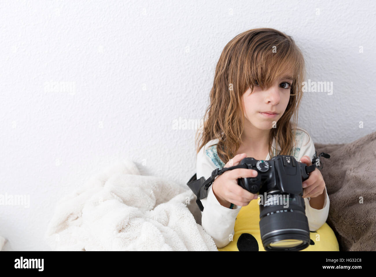 Girl with a camera in her hands, sitting on a bed. Horizontal shot with ...