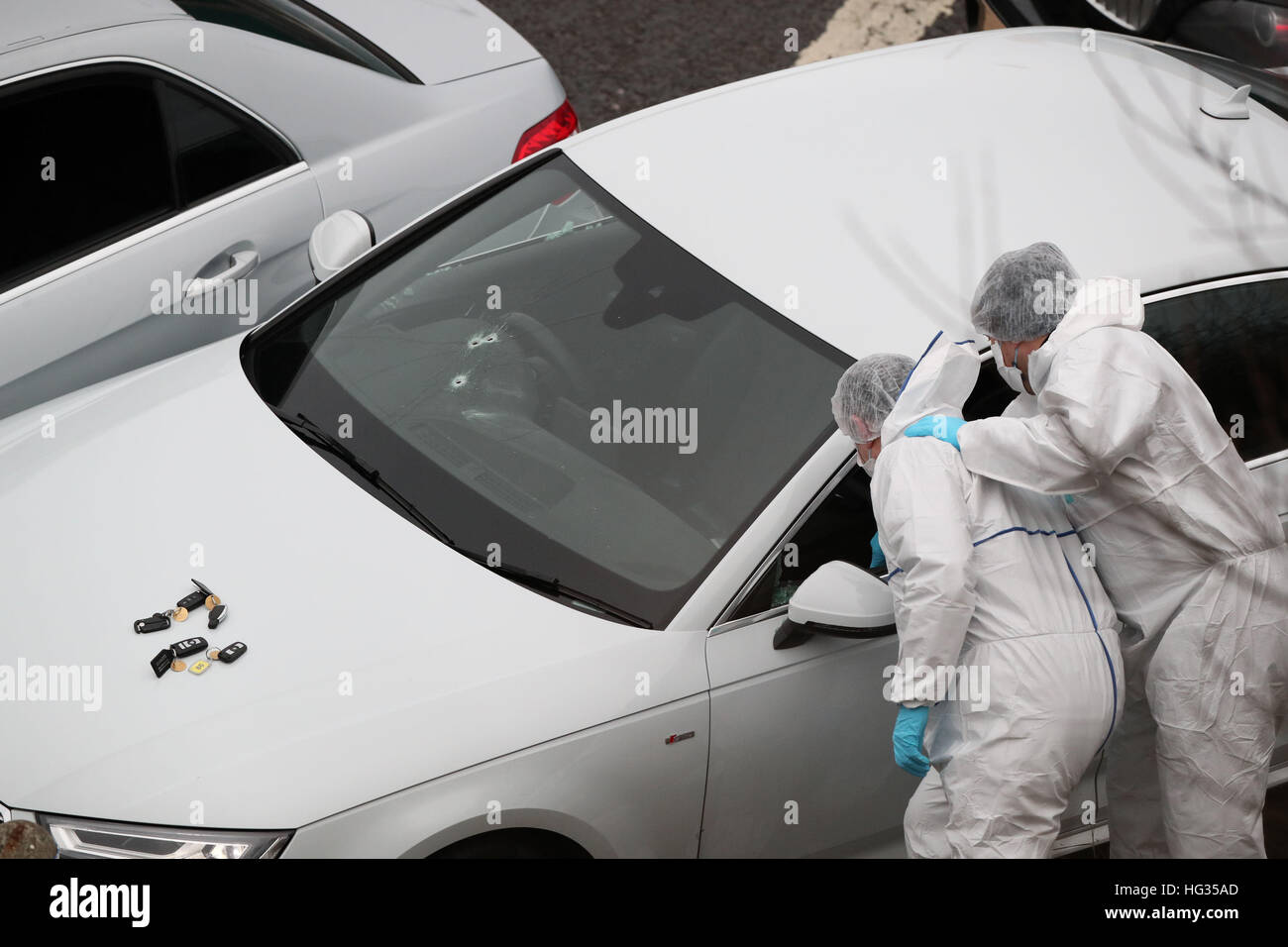Police forensics officers examine a silver Audi with bullet holes in ...