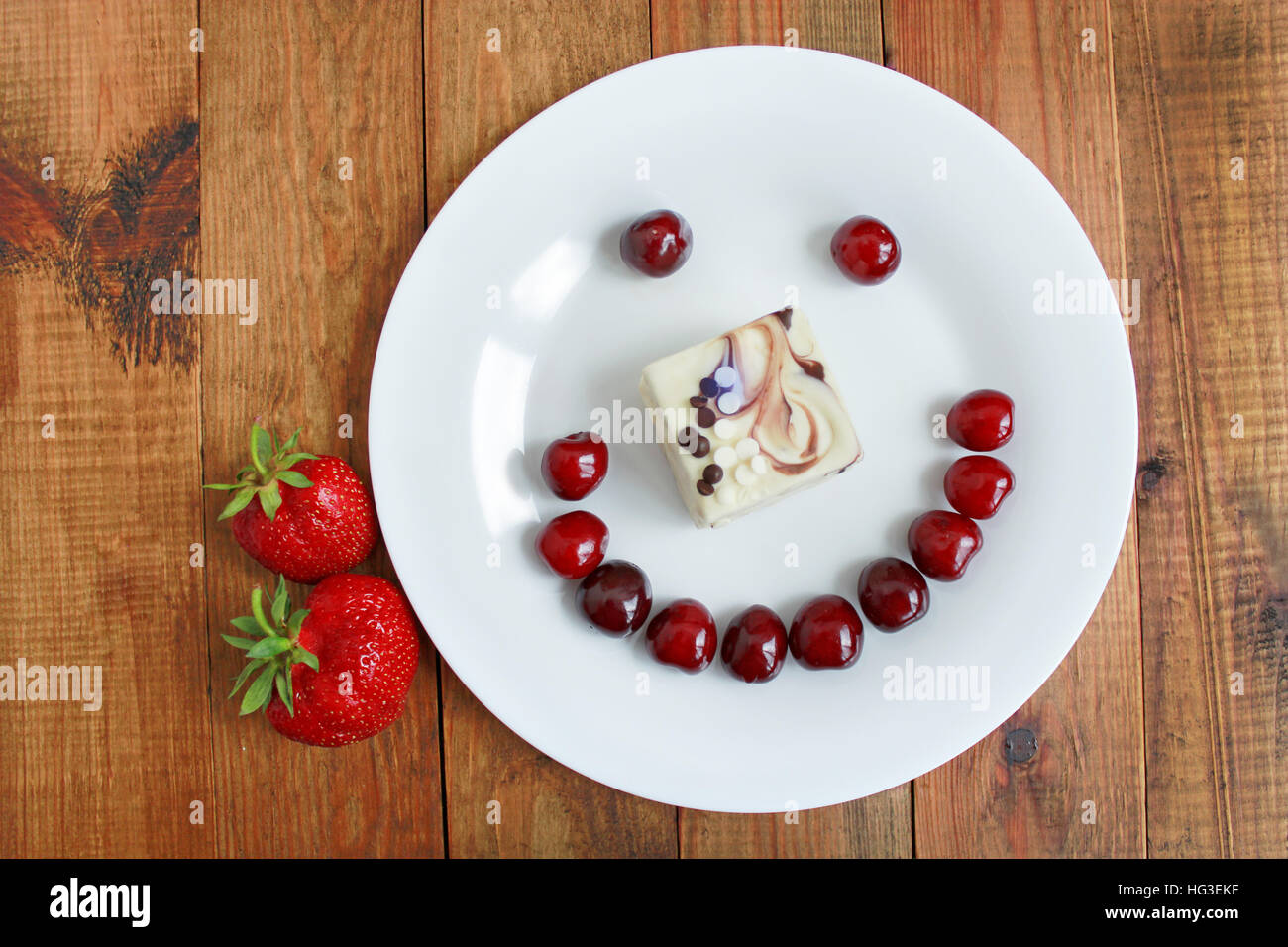 smile made from berries of ripe red cherries on the white plate and ...