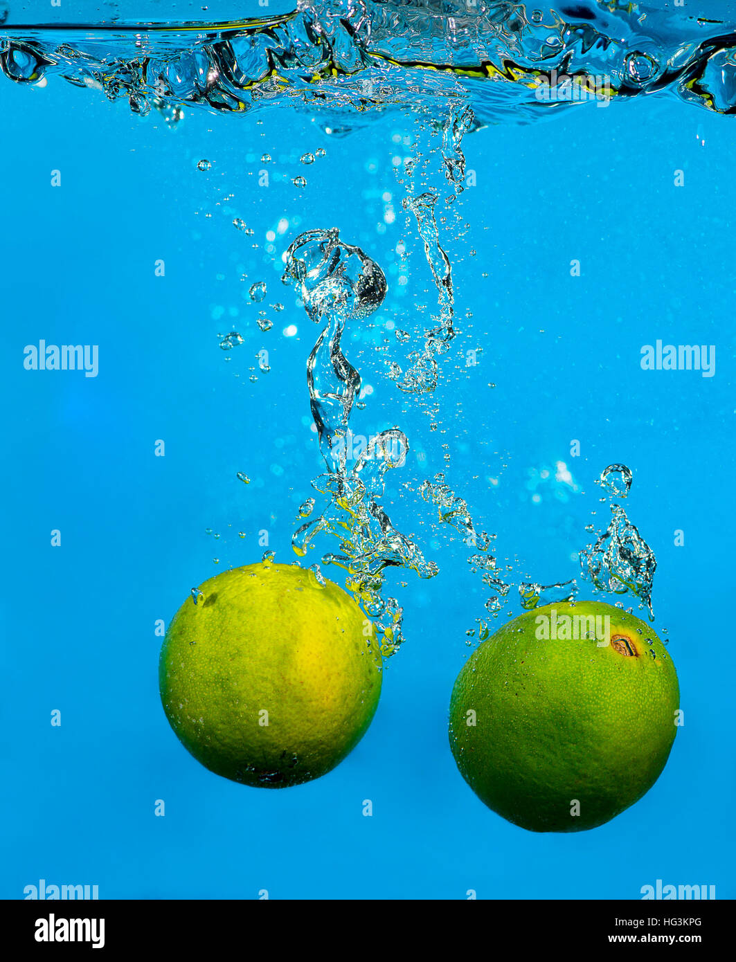 Lime splashing in water on blue background Stock Photo - Alamy