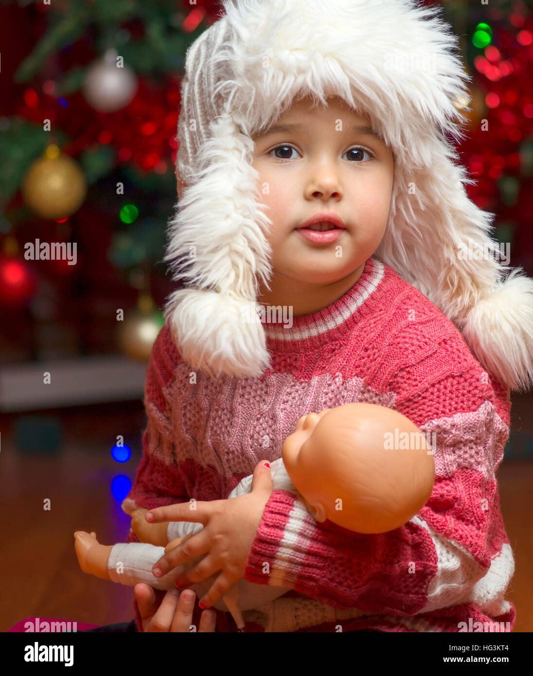 Girl with a favorite toy doll with Christmas lights background Stock ...