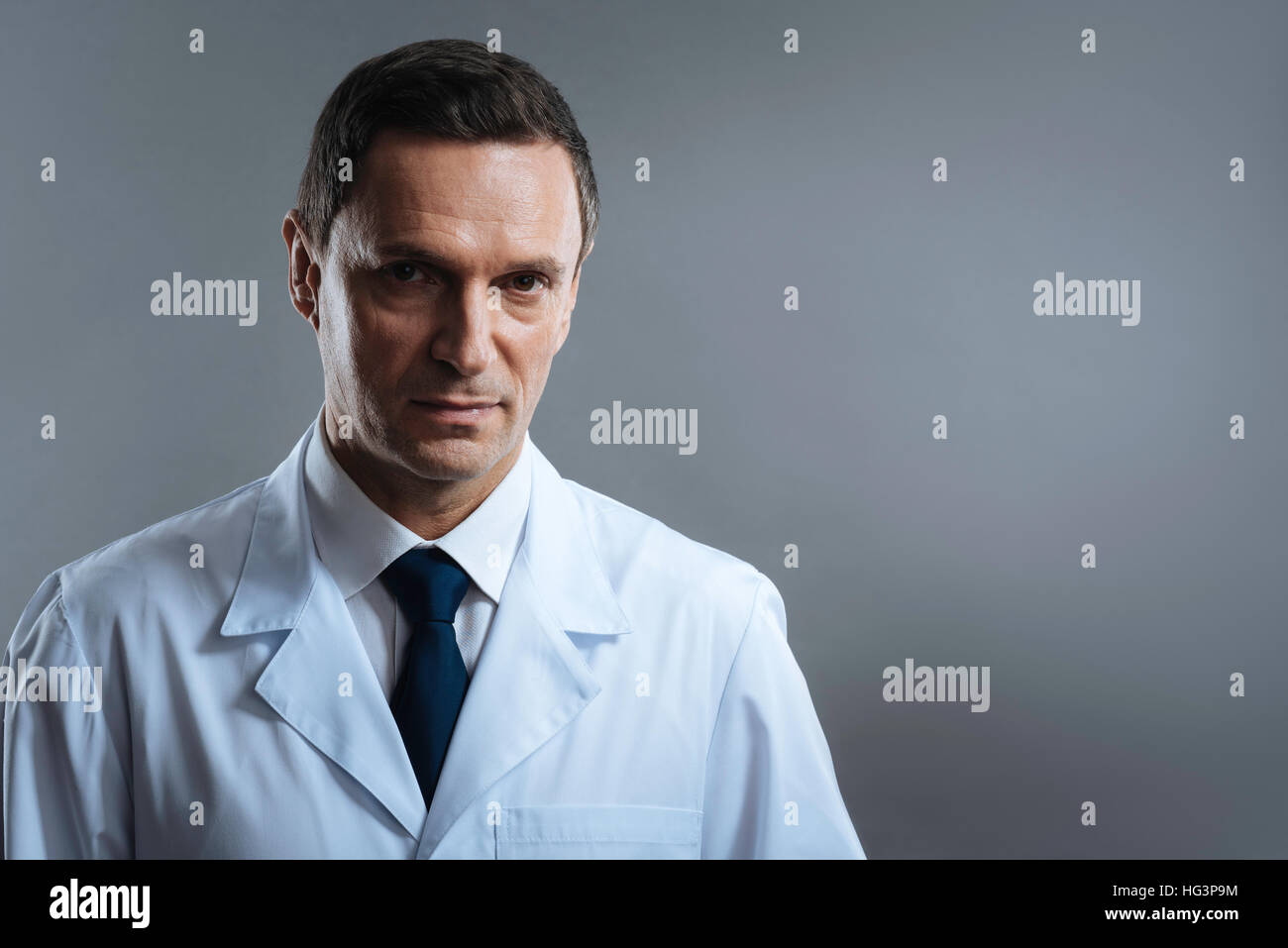 Handsome doctor standing on a grey background Stock Photo - Alamy