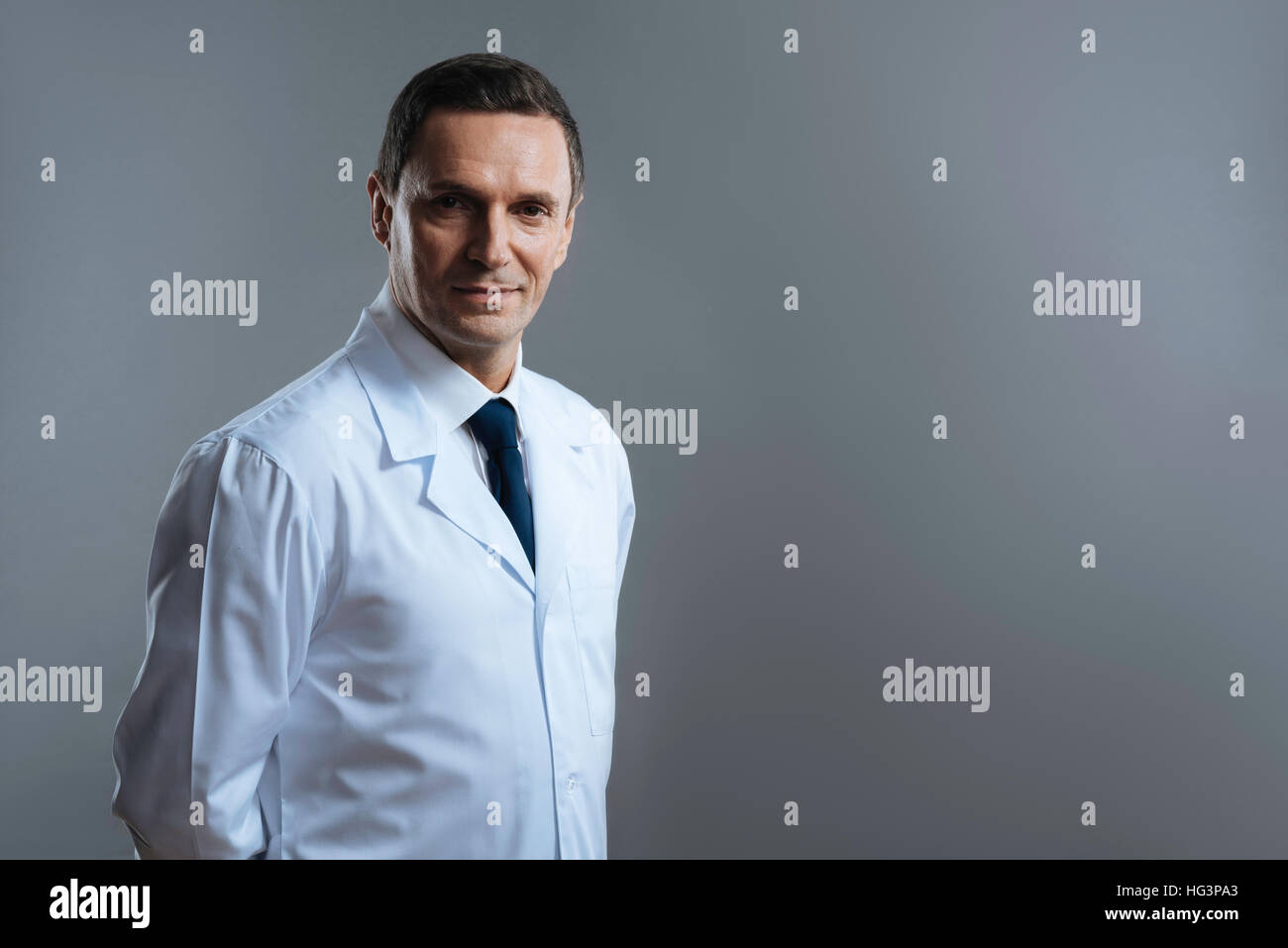 Smart doctor looking serious on a grey background Stock Photo - Alamy