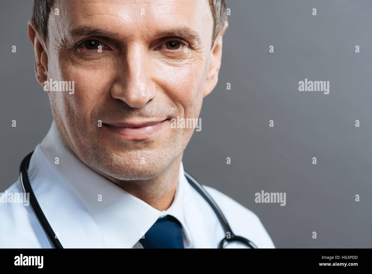 Portrait of handsome doctor smiling on a grey background Stock Photo ...