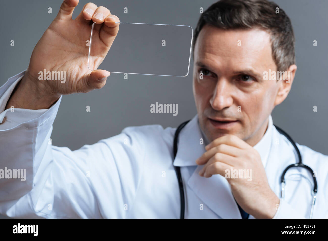 Concentrated doctor looking through glass Stock Photo - Alamy