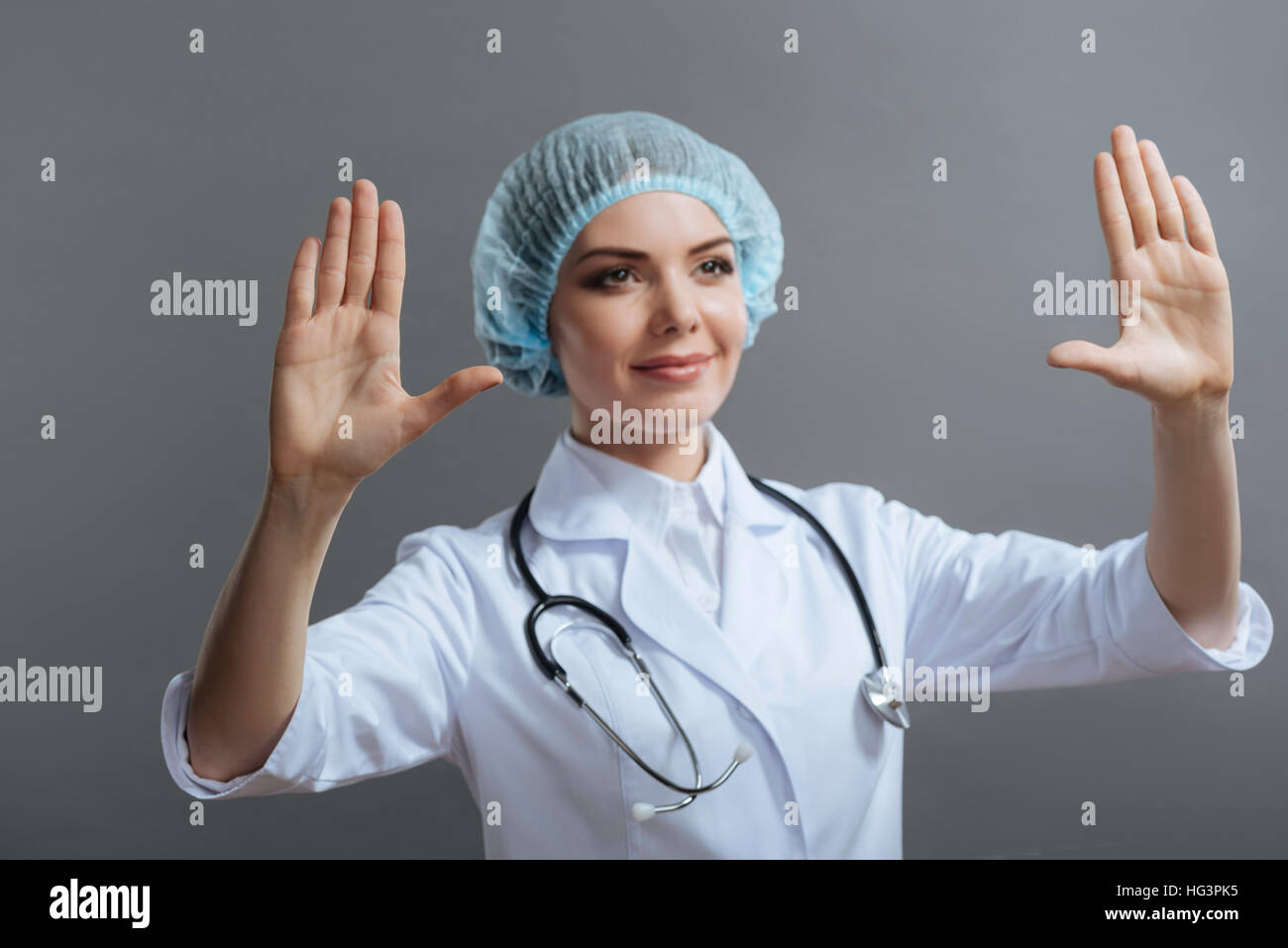 Female doctor putting hands up on grey background Stock Photo - Alamy