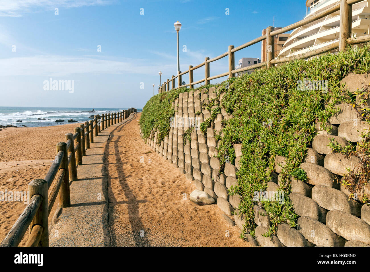 Retaining wall and wooden barrier on empty beach against blue skyline ...