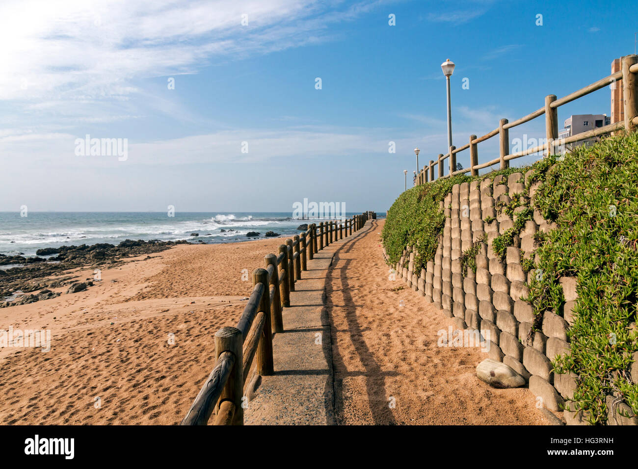 Retaining wall and wooden barrier on empty beach against blue skyline ...