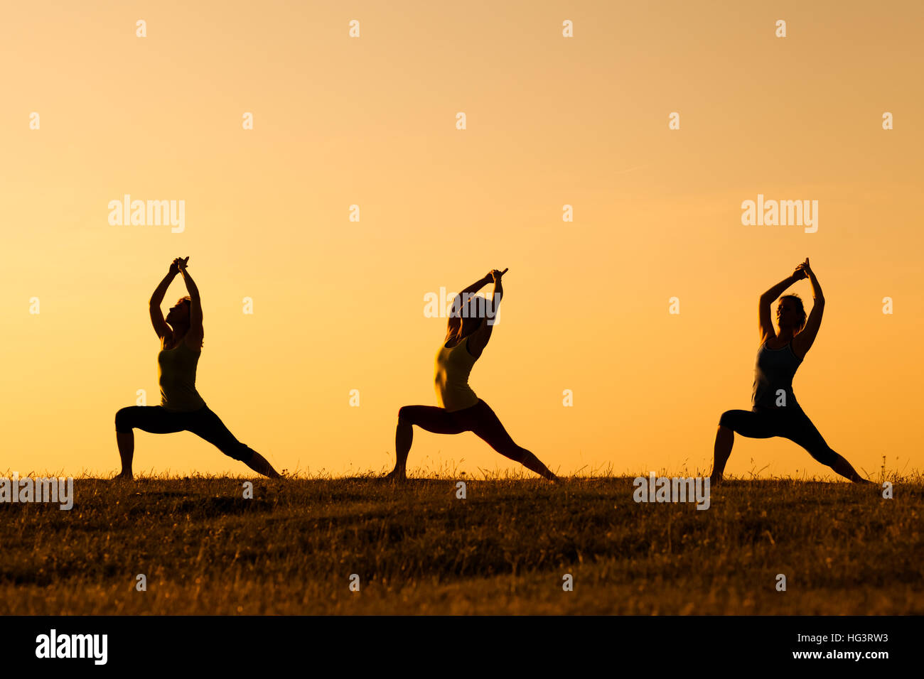 Three girls are practicing yoga at sunset Stock Photo - Alamy