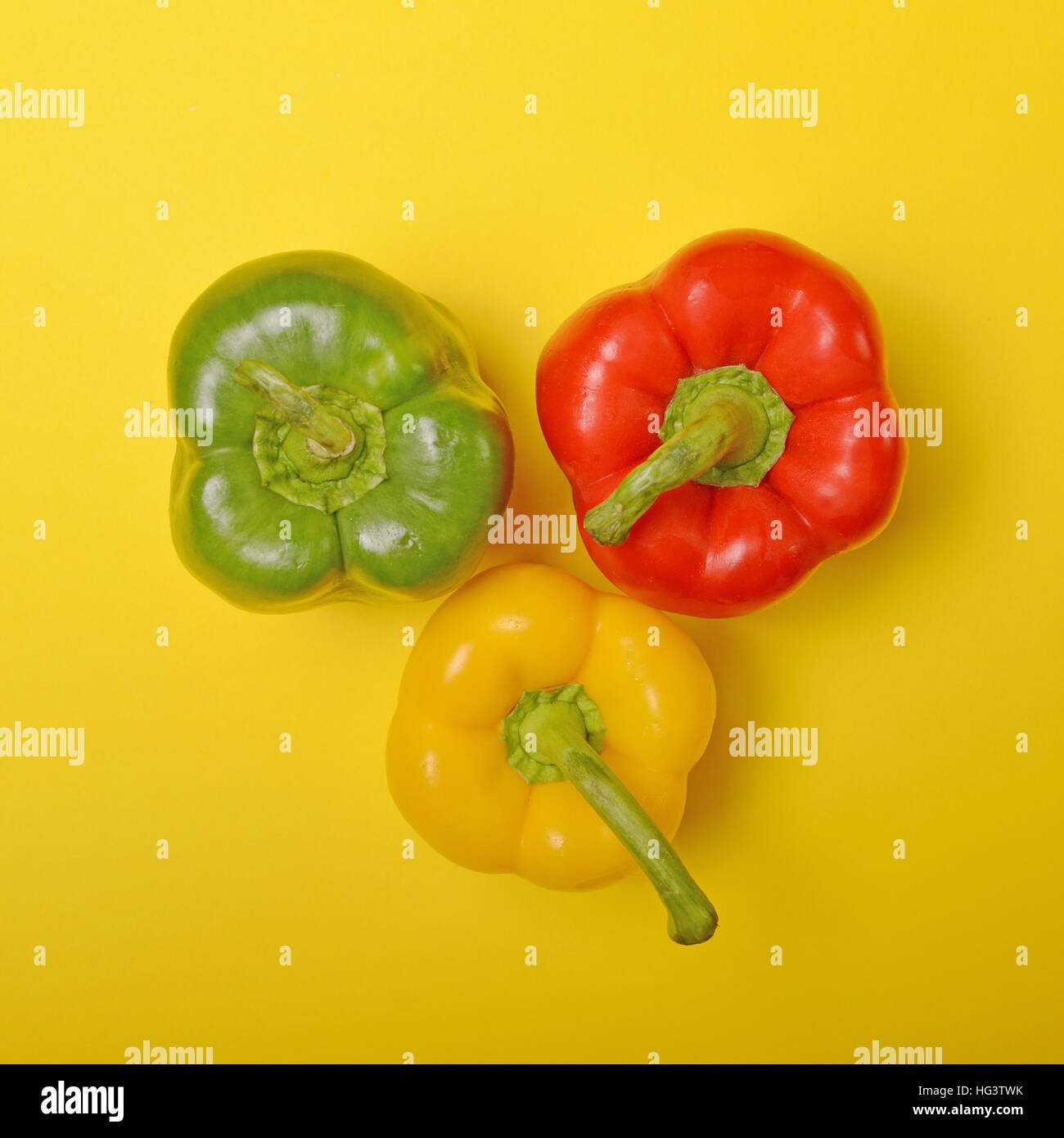 Three colorful paprikas on yellow background - Minimal flat lay view ...