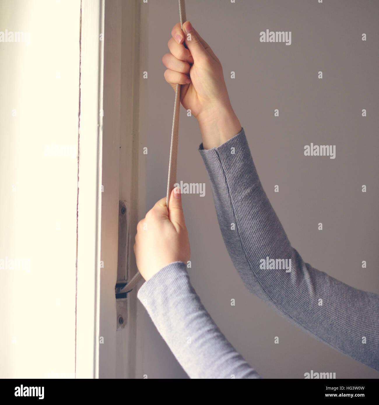 Woman opening curtains in living room Stock Photo - Alamy