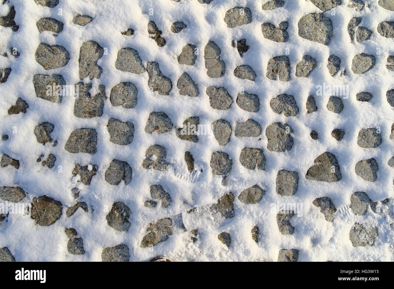 sidewalk made of cobblestone, partially covered by the snow Stock Photo ...