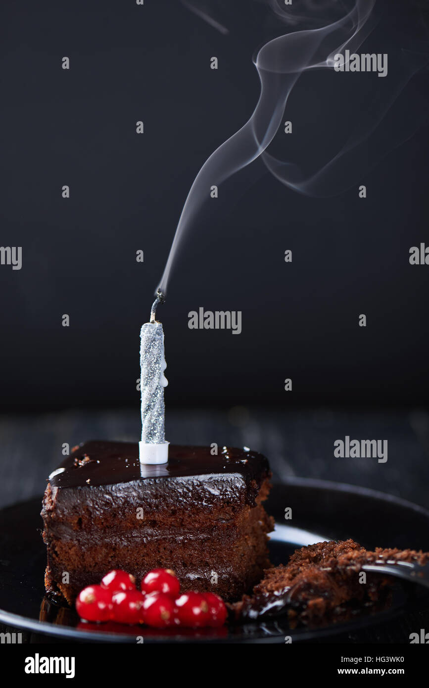 Slice of chocolate cake with a single lit candle Stock Photo - Alamy