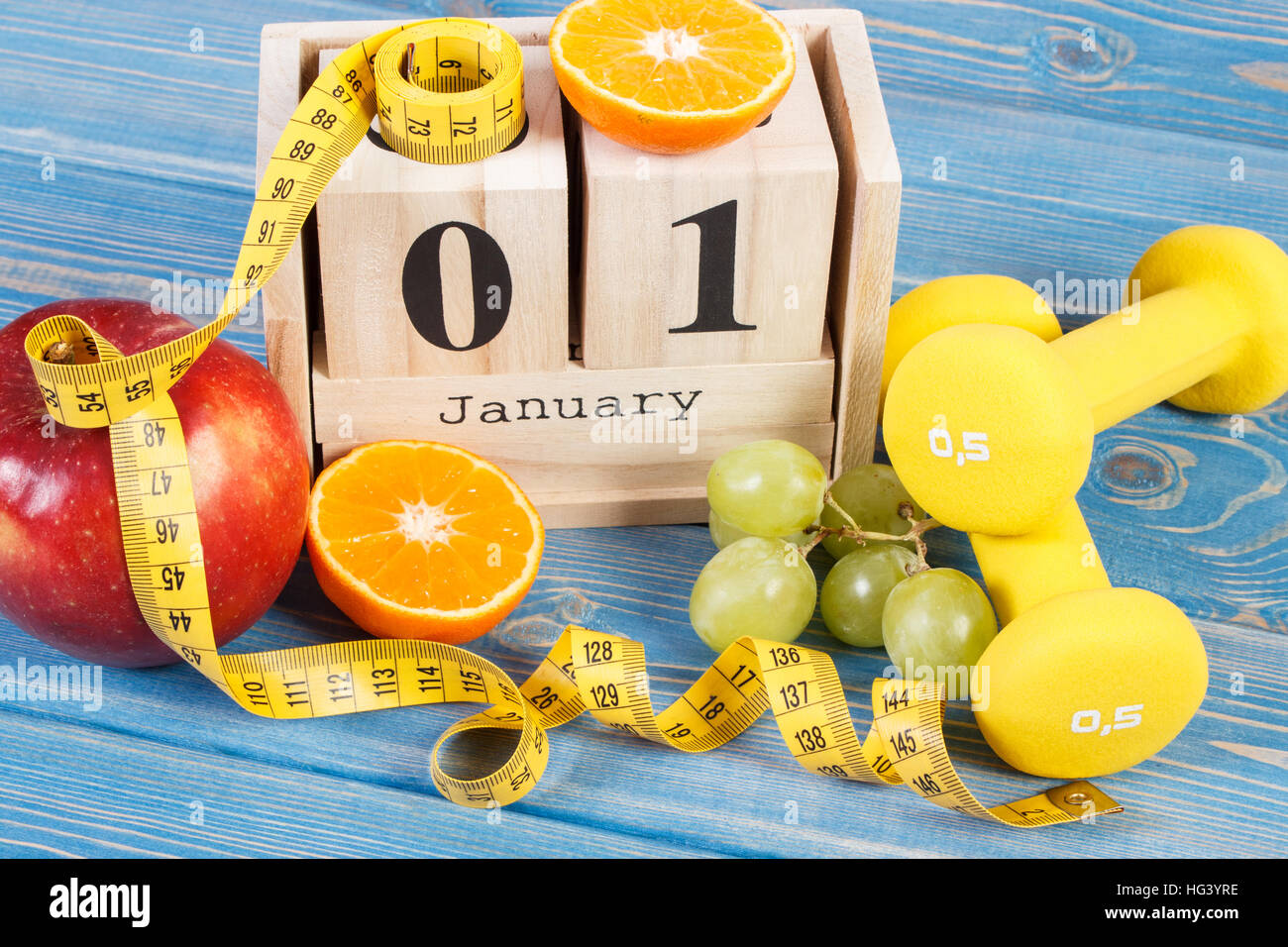 January 1 on cube calendar, fresh fruits, dumbbells and tape measure ...